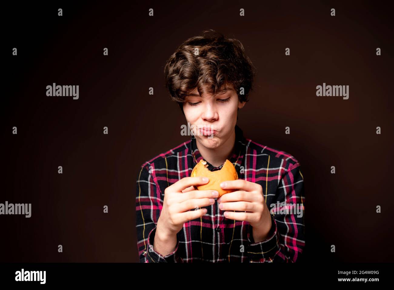 closeup photo of young man chew junk food on dark background Stock ...