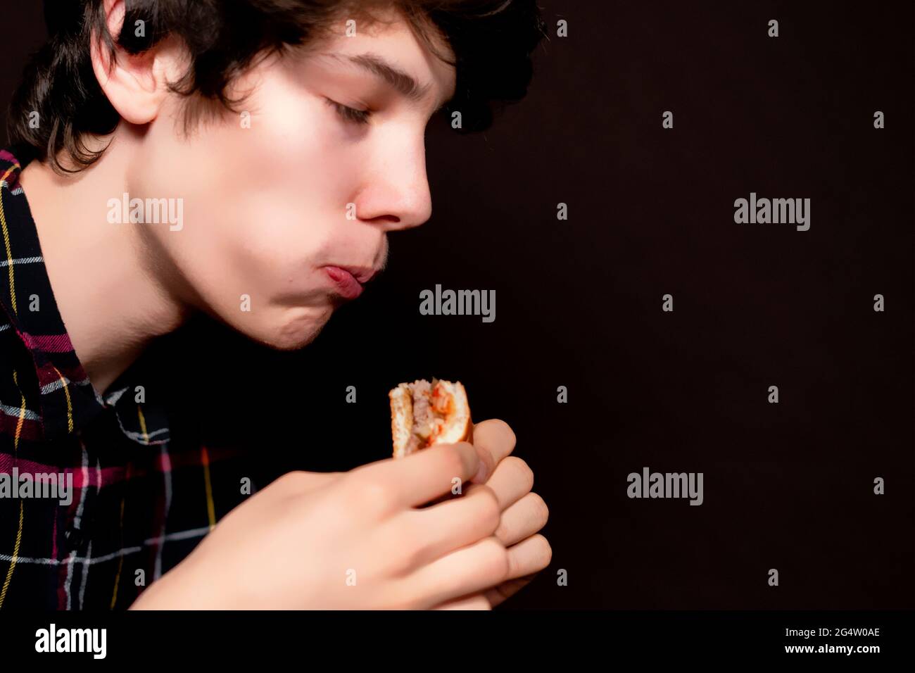 closeup photo of young man chew junk food on dark background Stock ...