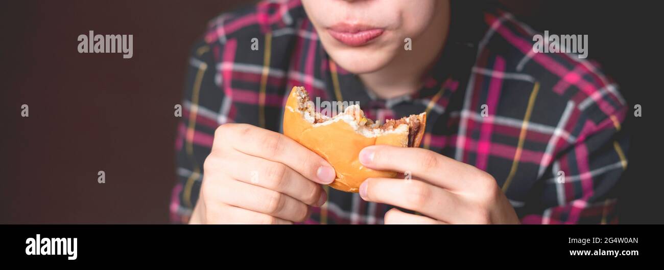 closeup photo of young man chew junk food on dark background Stock ...