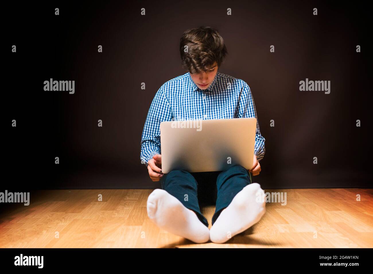 portrait of handsome happy young man sit on floor use laptop and wear ...