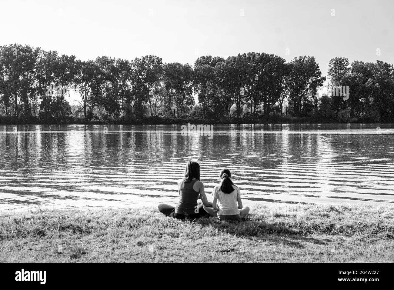 Rear view of a couple of Caucasian females sitting on the riverside in ...