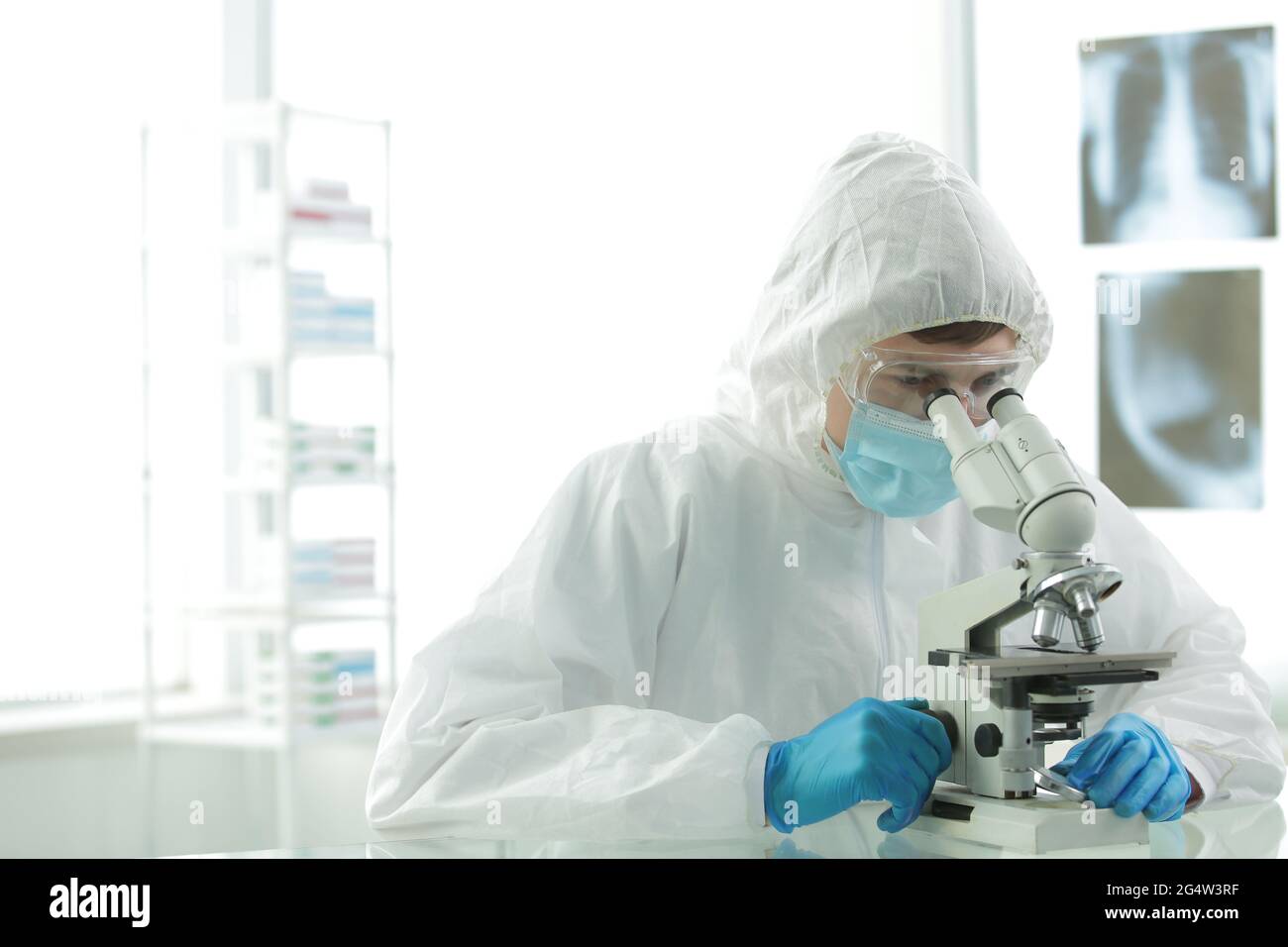 Doctor in a protective suit with gloves adjusts protective glasses near ...