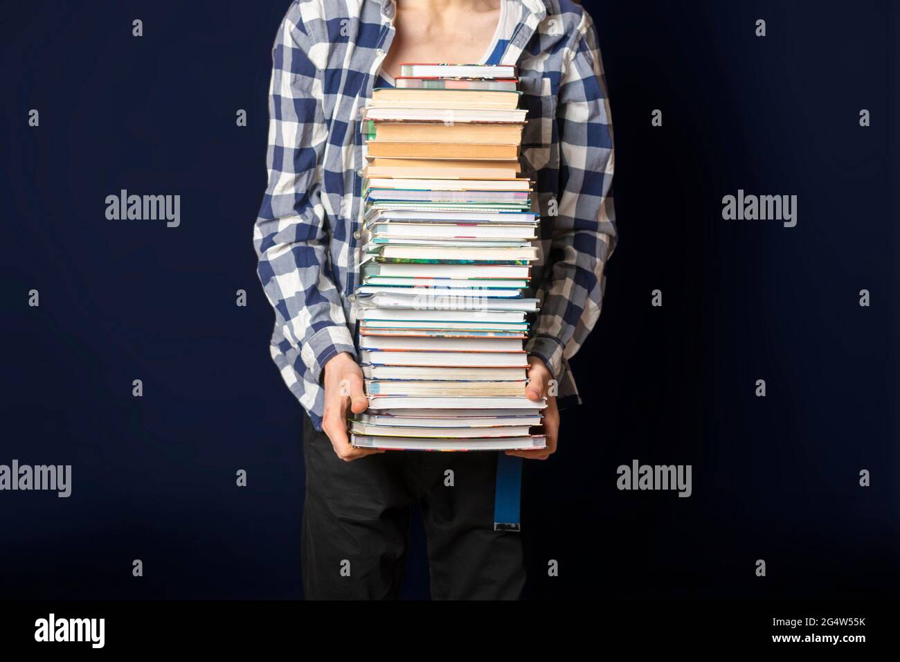 casual student carry huge stack of books on dark background Stock Photo ...