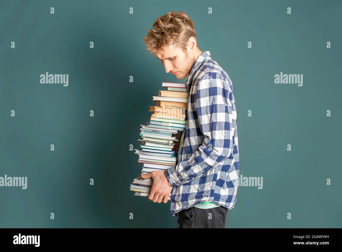 casual student carry huge stack of books on dark background Stock Photo ...