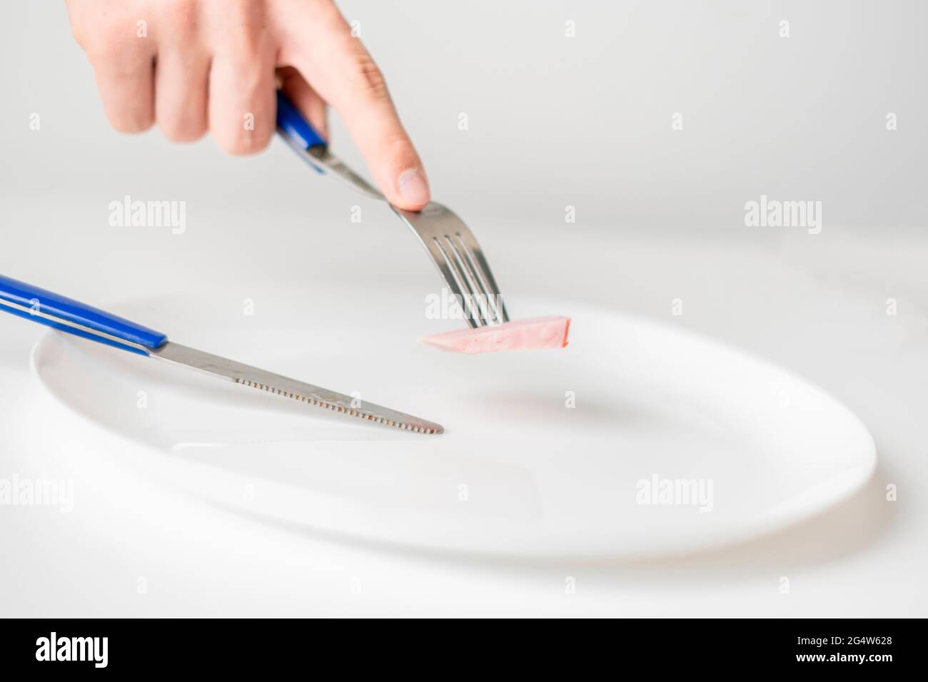person hands with fork and knife eat small portion of food. anorexia ...