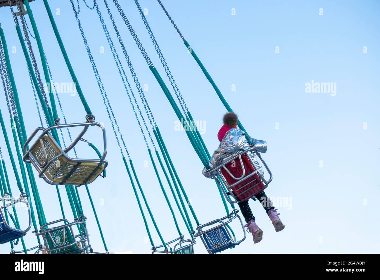 child having fun riding on a chain carousel in the amusement park Stock ...