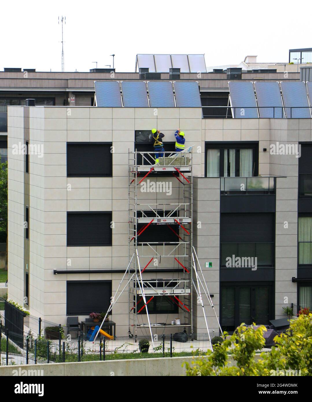 Two workmen repairing water ingression behind cladding on a 1 year old ...