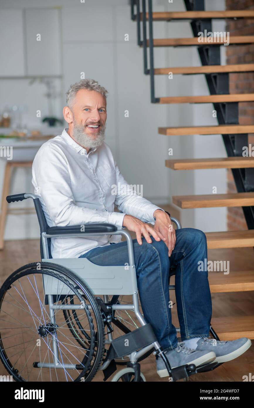 Handicapped gray-haird man in white shirt and jeans at home Stock Photo ...