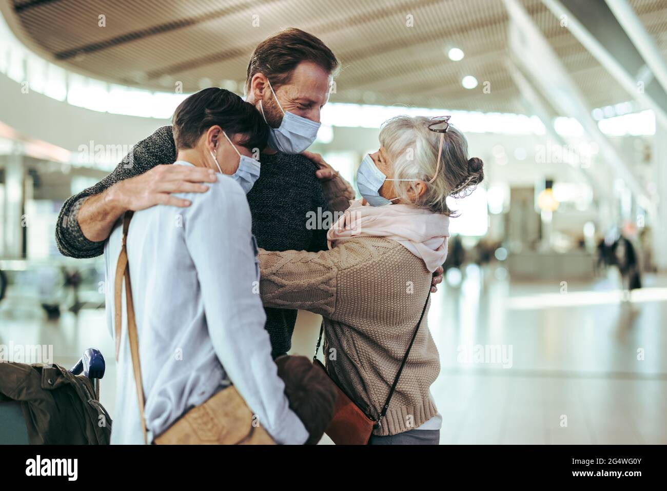 Senior woman embracing and welcoming family at airport terminal after ...