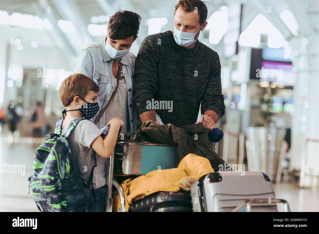 Tourist family going on back home during pandemic. Couple looking at ...