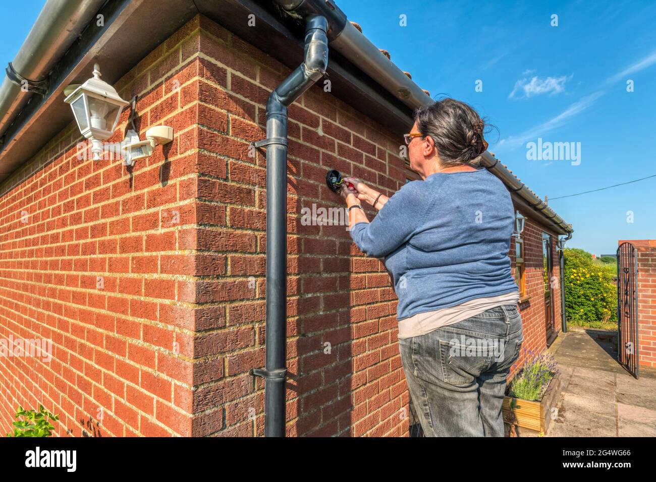 Woman fixing outside lights on an external wall Stock Photo - Alamy