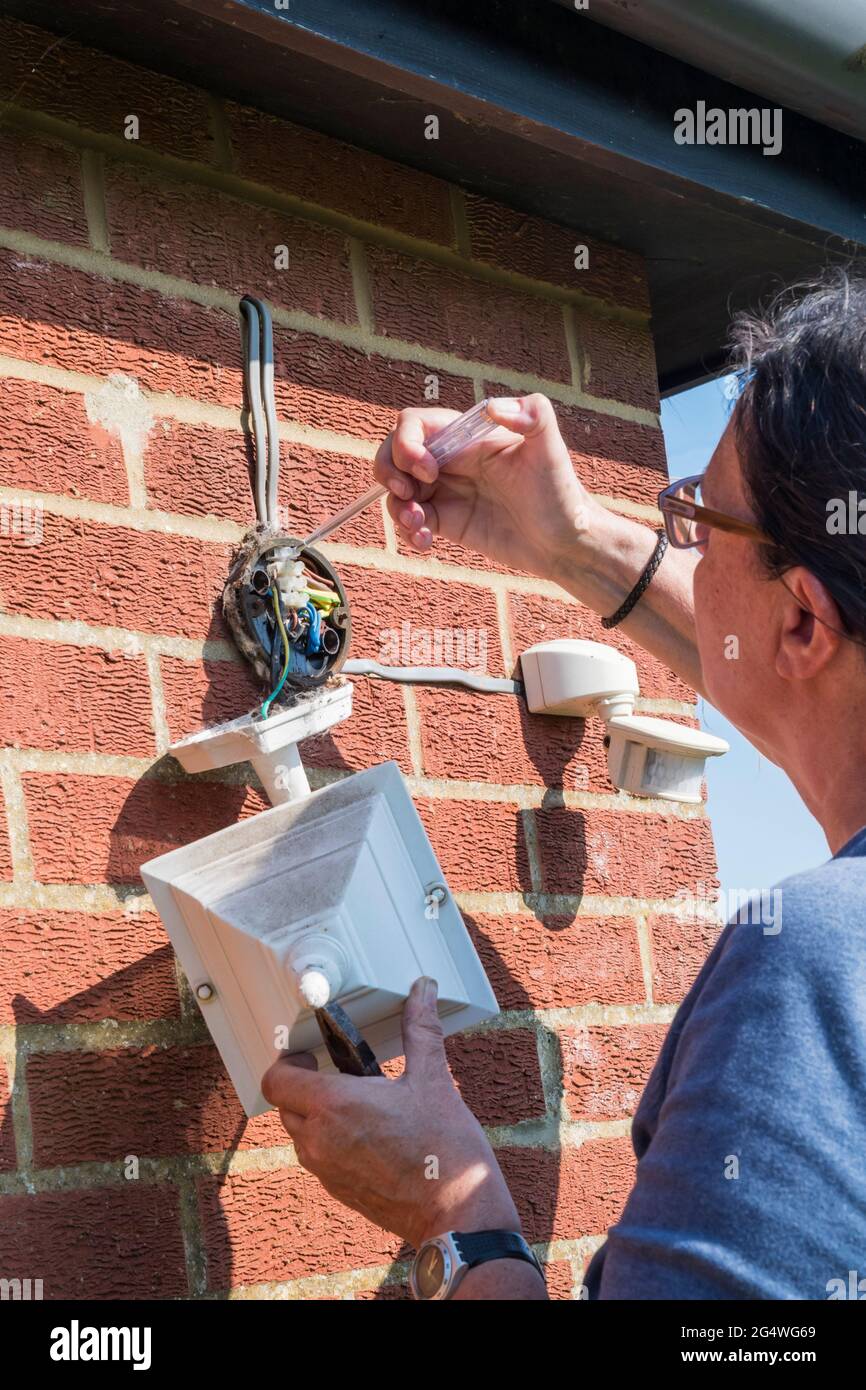 Woman fixing outside lights on an external wall Stock Photo - Alamy