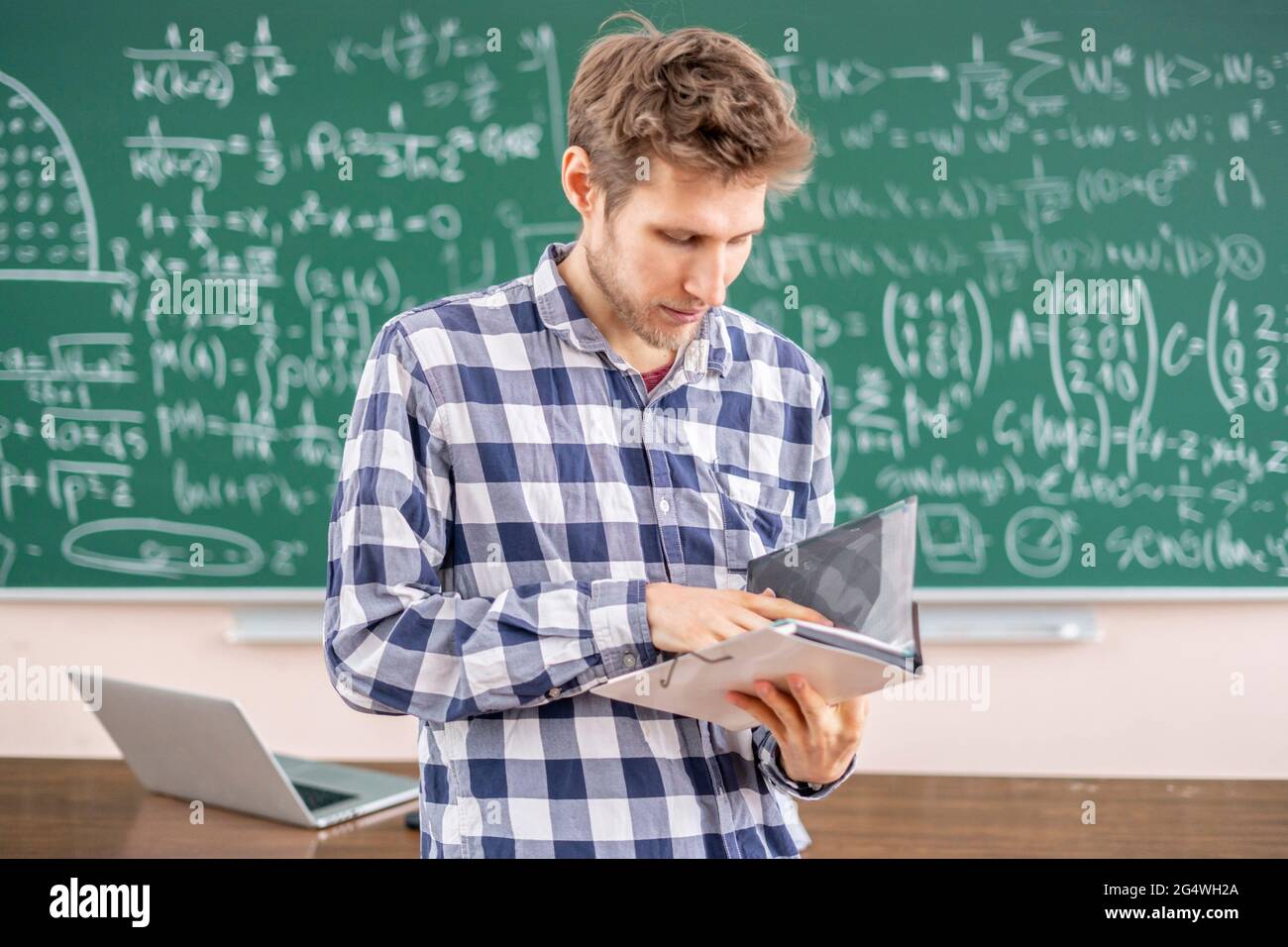 happy young speaker portrait giving a lecture in front of blackboard ...