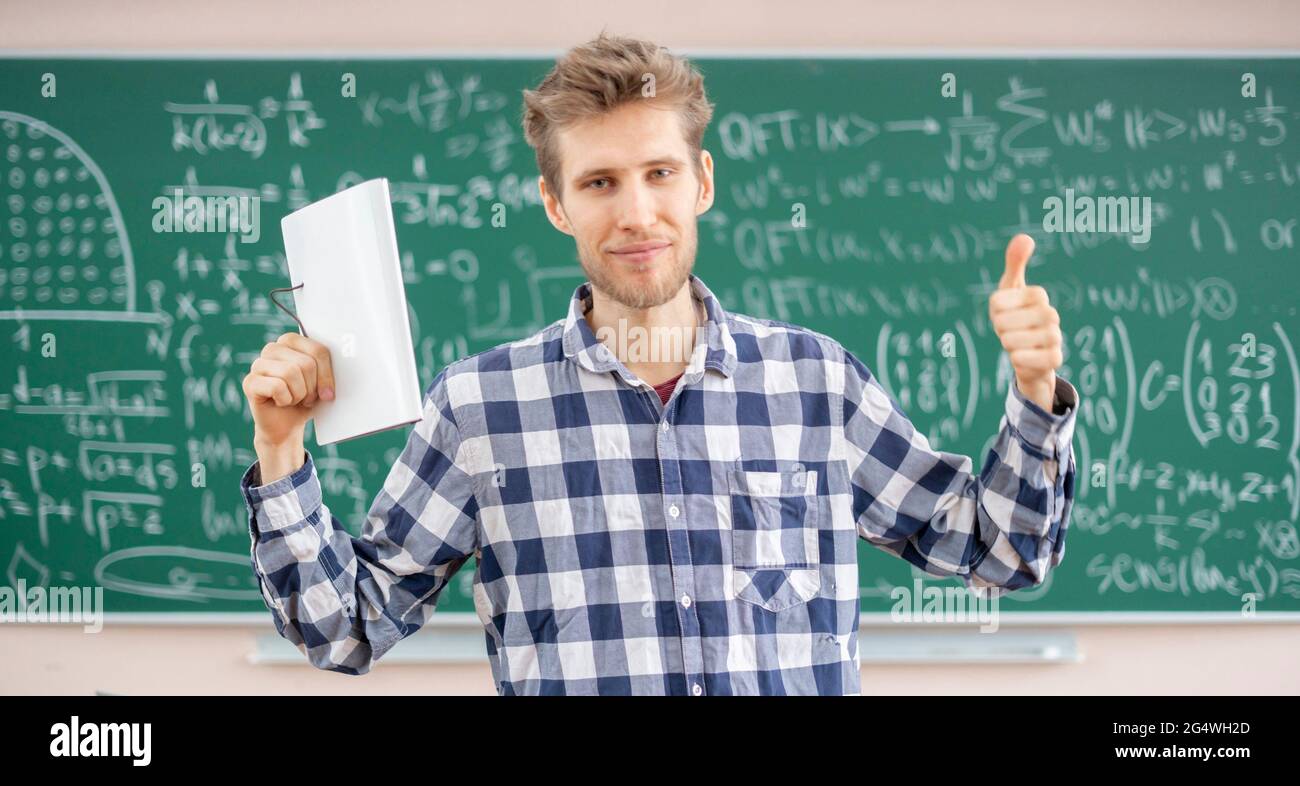 happy young speaker portrait giving a lecture in front of blackboard ...