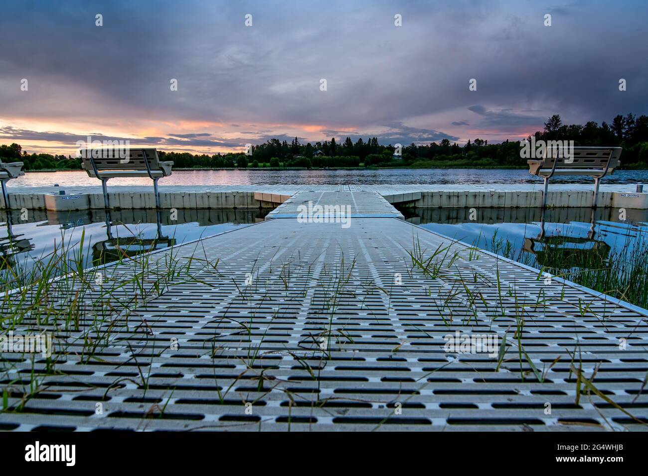 Beautiful sunset over the big pier with dock benches reflecting in a ...