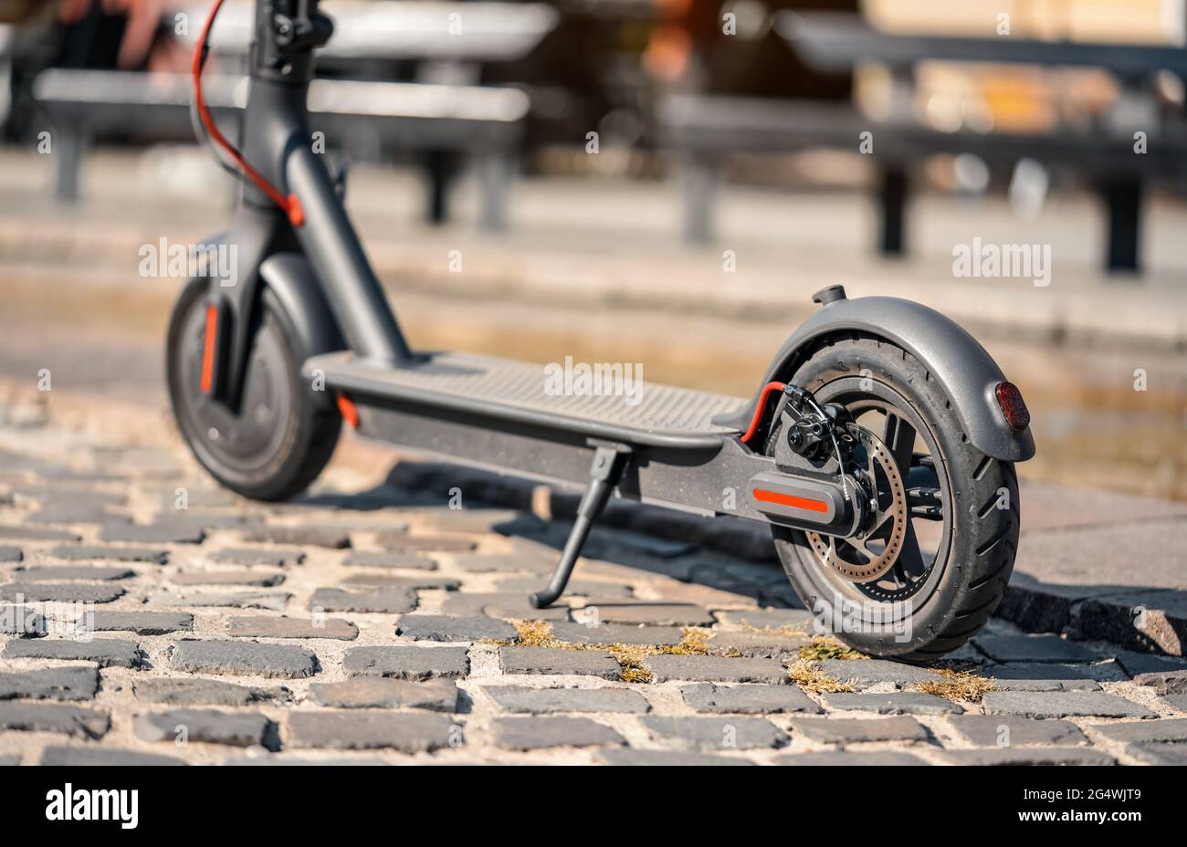 Electric scooter parked on tiled cobblestone pavement - closeup detail ...
