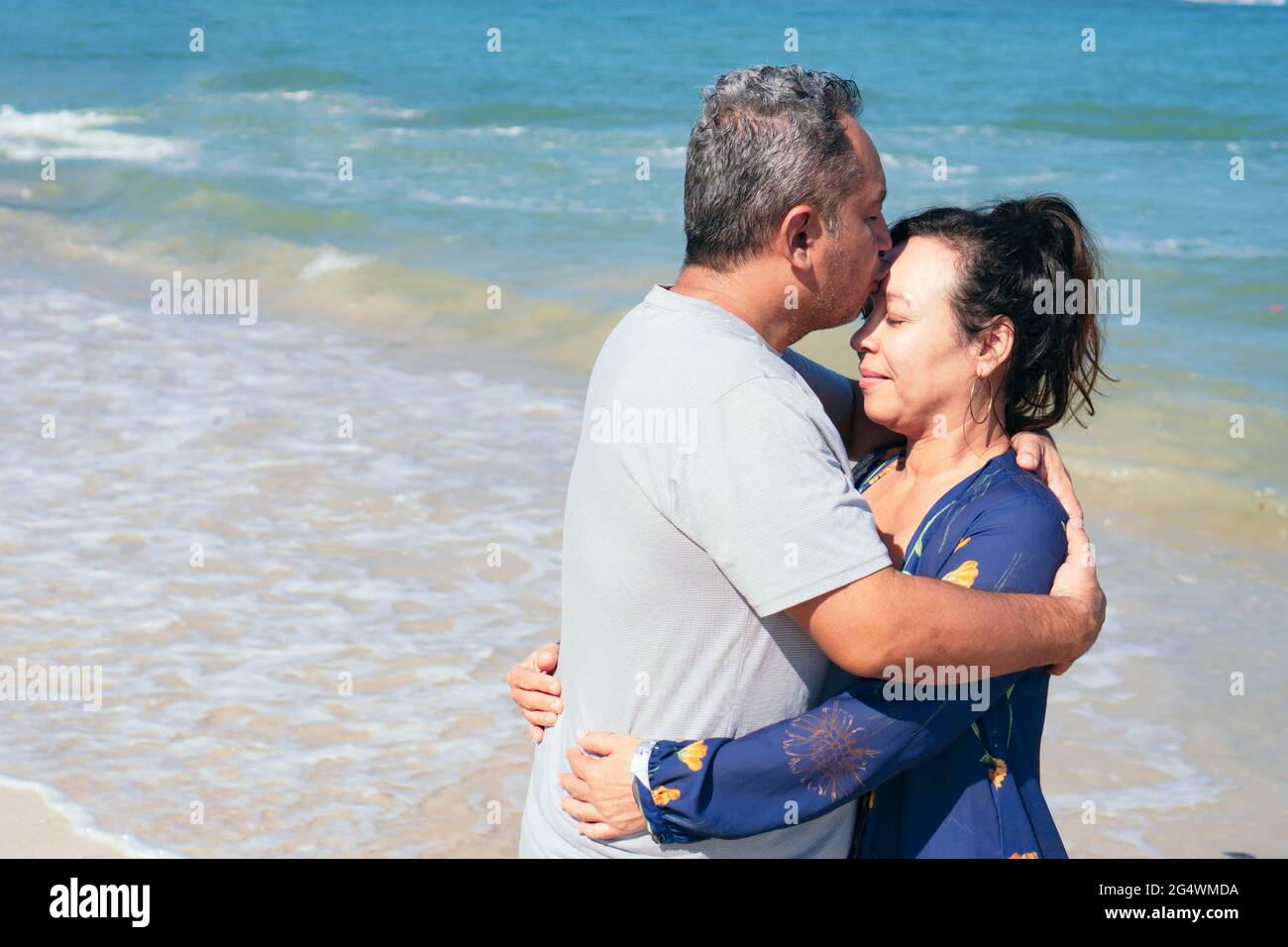 Couple standing cuddling beach hi-res stock photography and images - Alamy