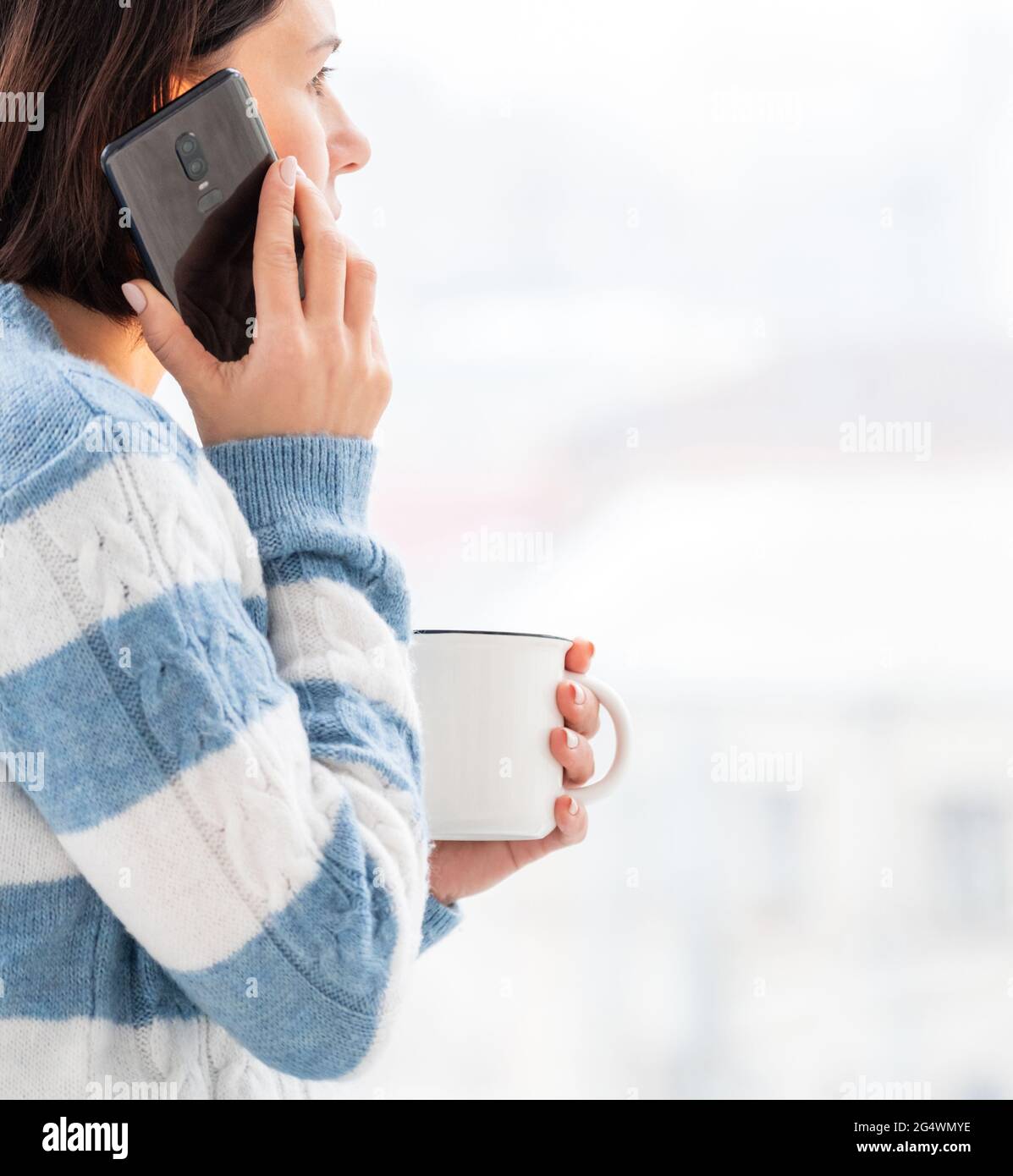 Girl talking on phone while drinking from cup Stock Photo - Alamy