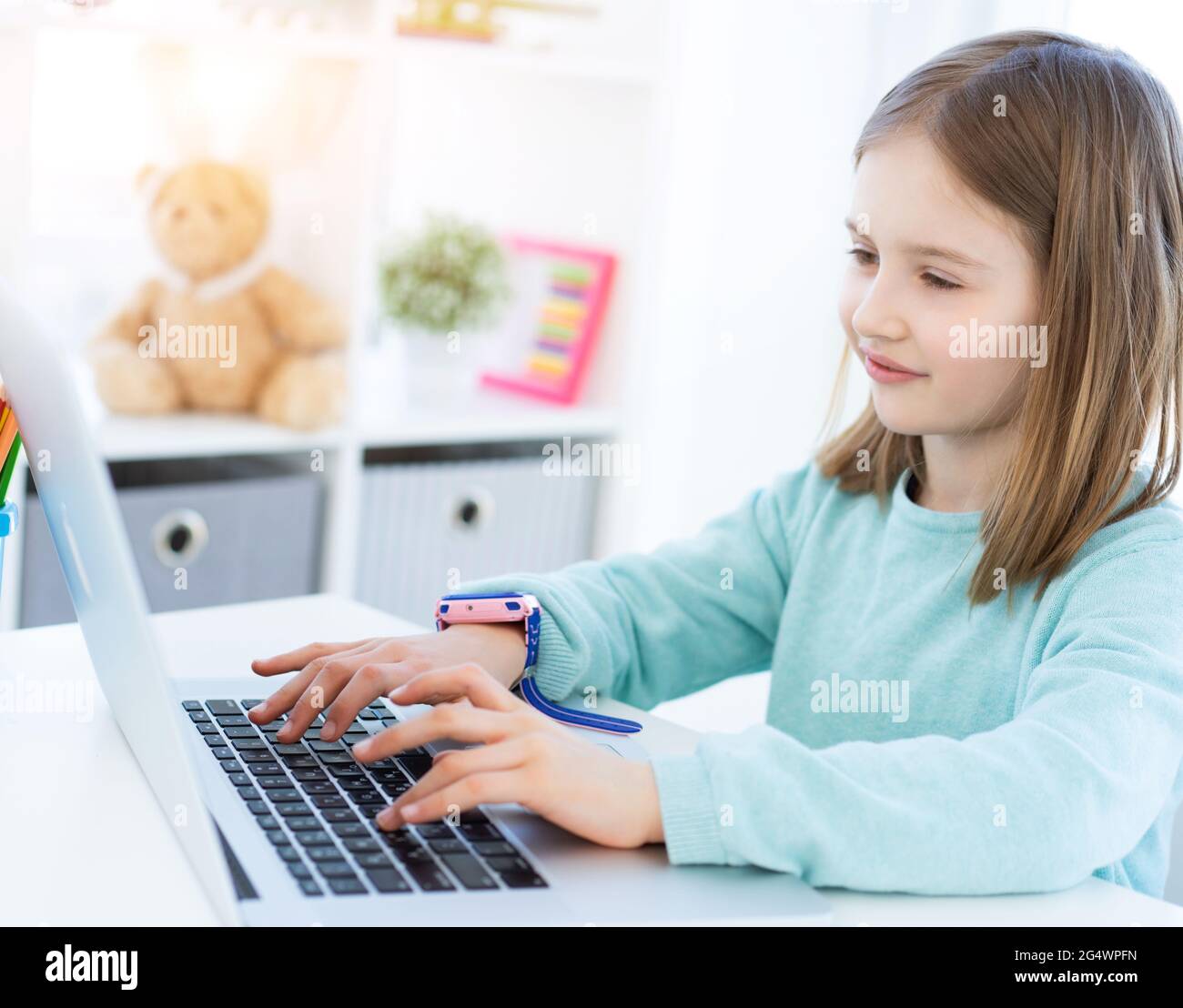 Cute little girl using computer in light room Stock Photo - Alamy