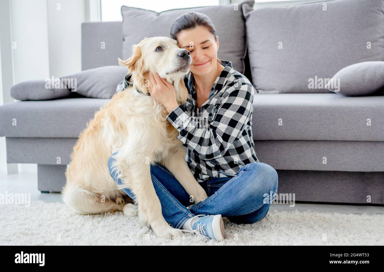 Beautiful woman cuddling lovely dog in light room Stock Photo - Alamy