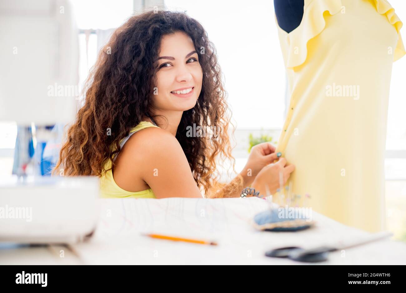 Smiling tailor pinning parts of dress in workshop Stock Photo - Alamy