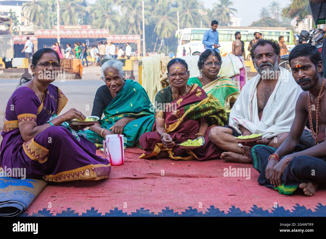 Group of male and female hindu worshippers seated cross legged on ...