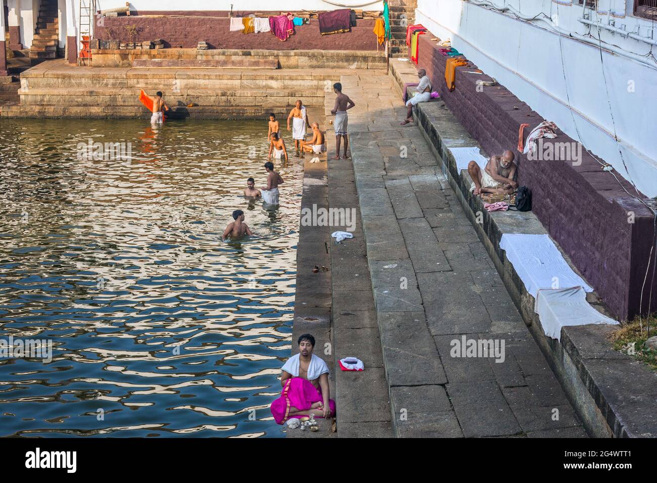 Indian males bathing in the sunshine at the Madhwa Sarovar pushkarni ...