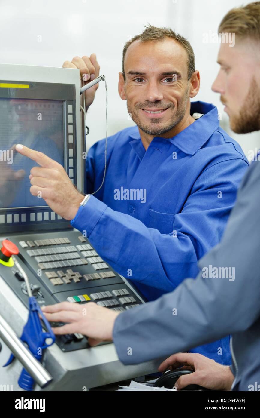 engineer teaching apprentices to use computerized processing machines ...