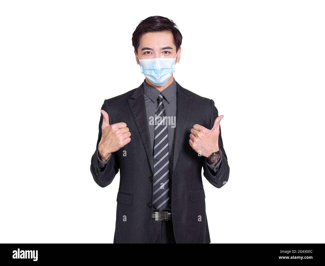 young businessman wearing medical mask, standing and showing thumbs up ...