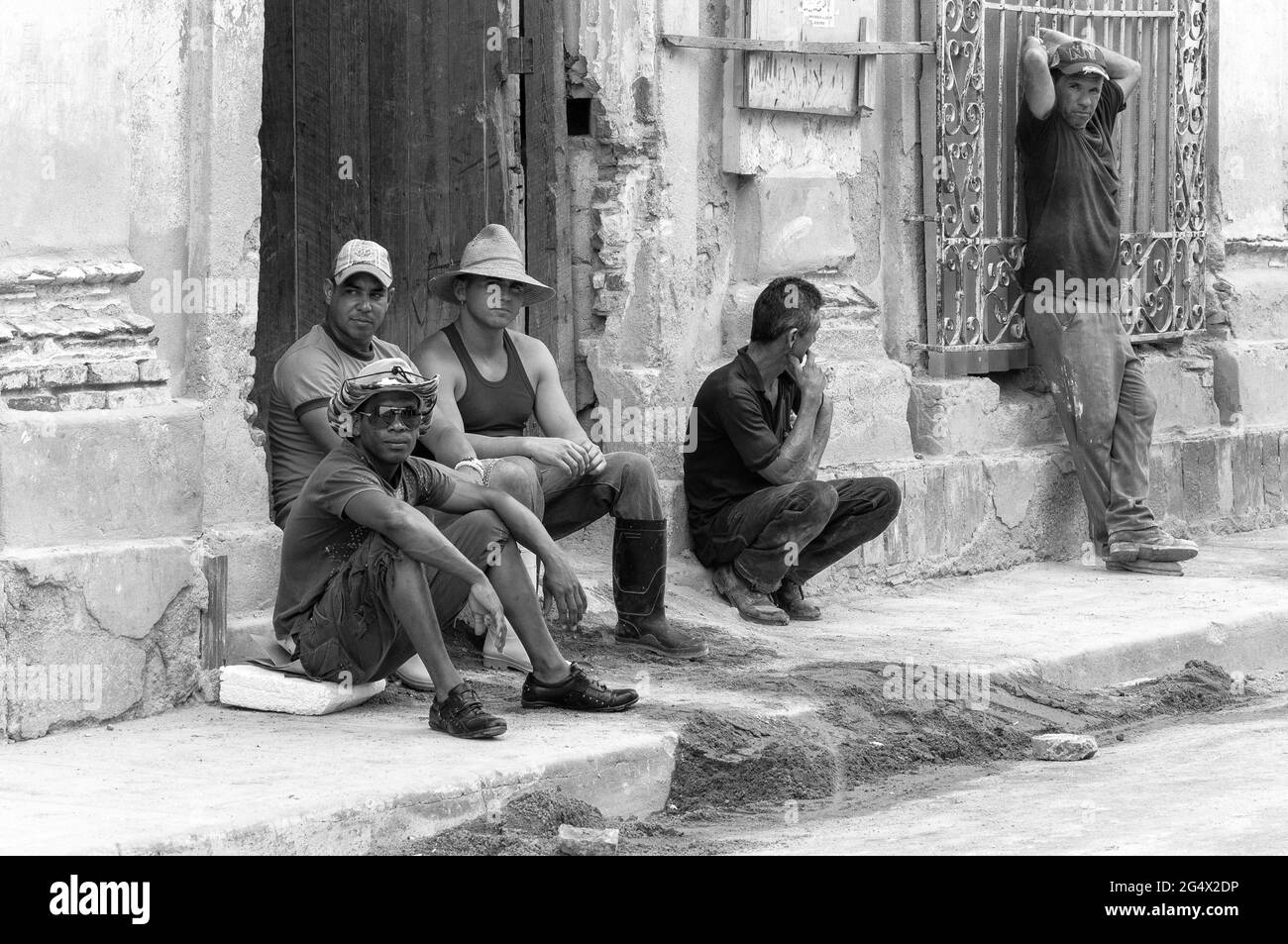 Cuban construction workers sitting leisurely in front of an old ...