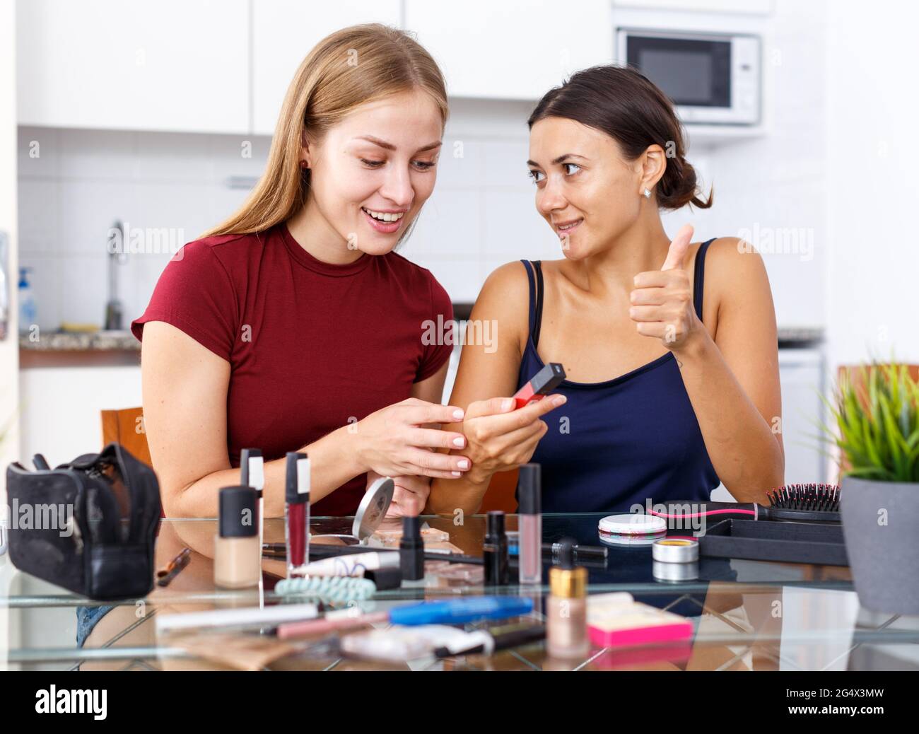 Smiling young girlfriend looking cosmetics before make-up in home ...