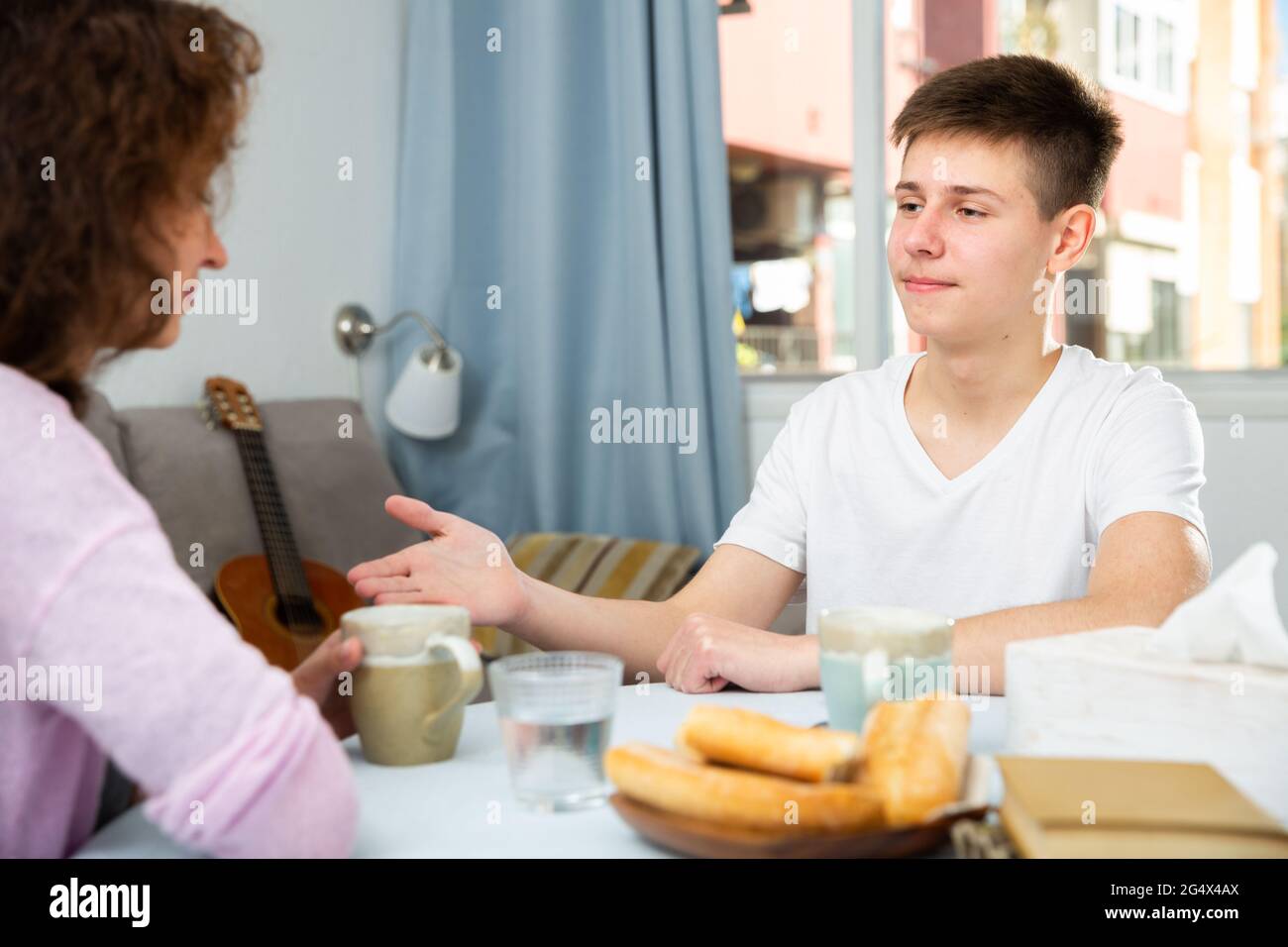 Cheerful teenage boy telling story to mother Stock Photo - Alamy