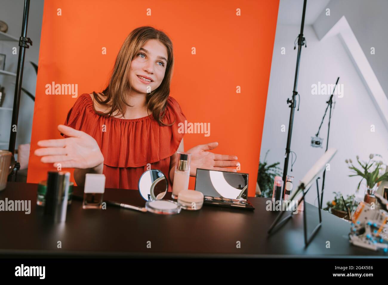 Teenage girl filming gesturing while vlogging make-up tutorial at home ...