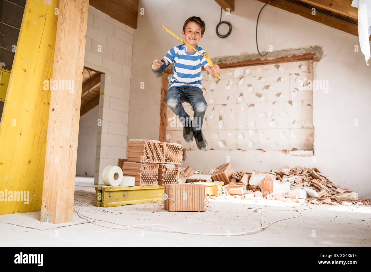 Boy with tape measure jumping at loft apartment during renovation Stock ...