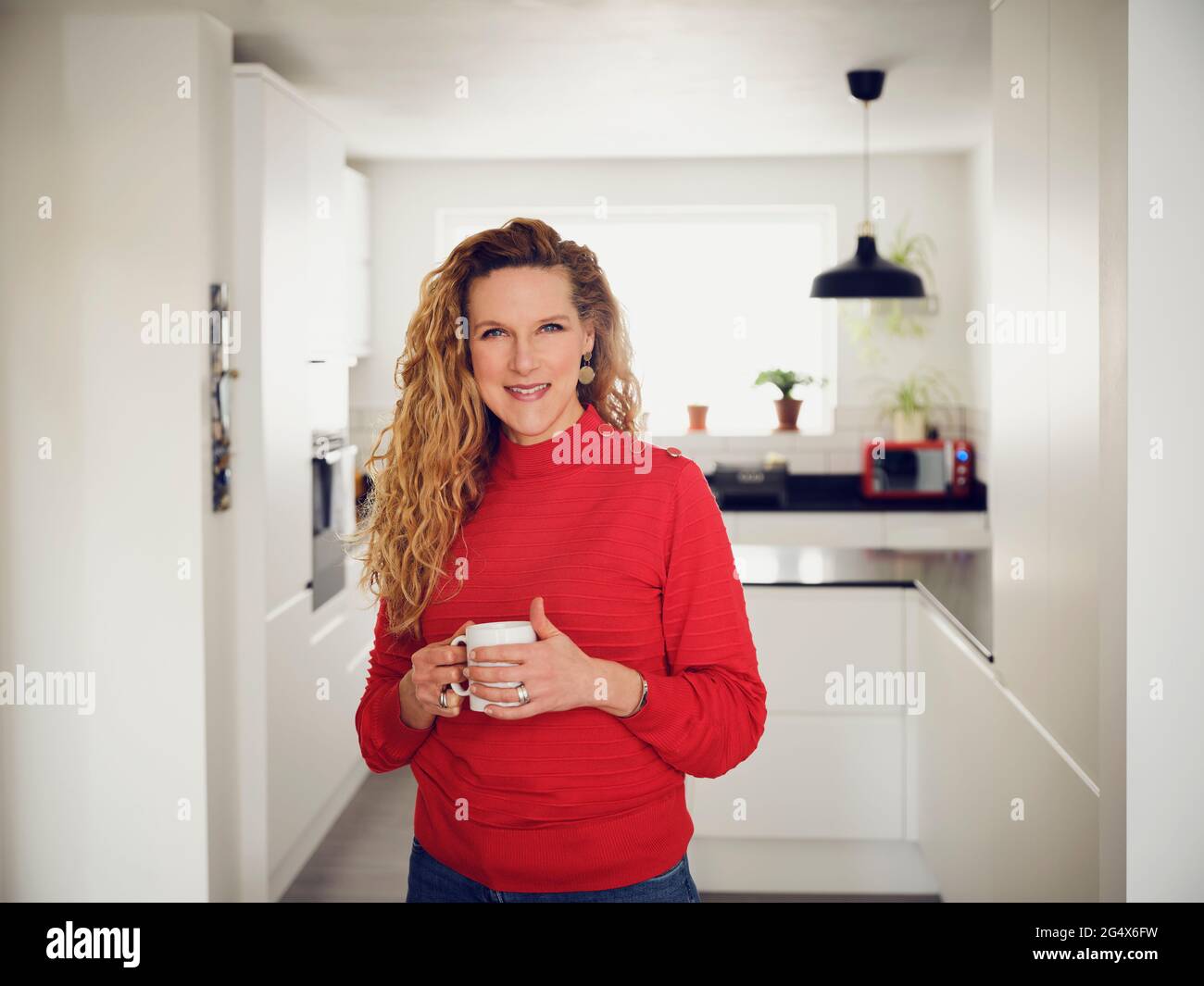 Woman standing in kitchen holding hi-res stock photography and images ...