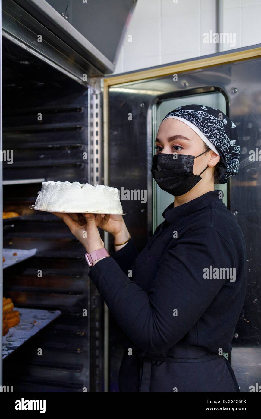 Female baker putting cake in display cabinet Stock Photo - Alamy