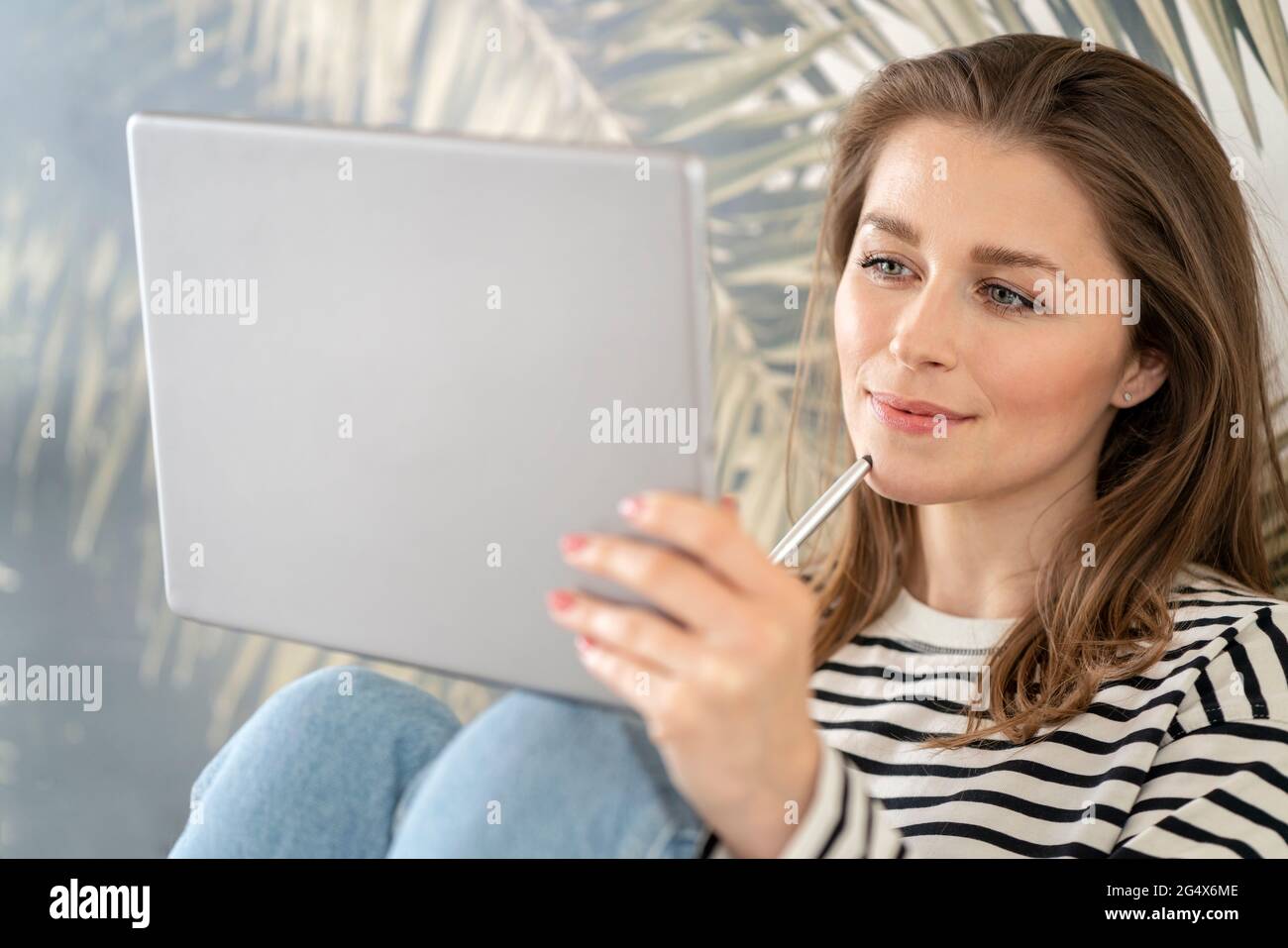 Thoughtful businesswoman with digitized pen looking at graphics tablet ...
