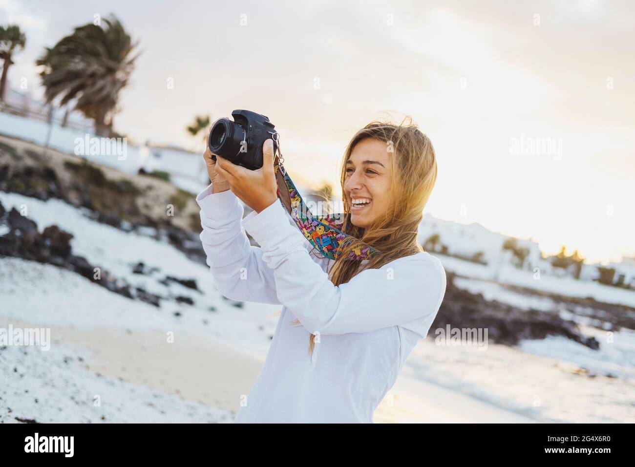 Smiling young woman photographing through camera at beach Stock Photo ...