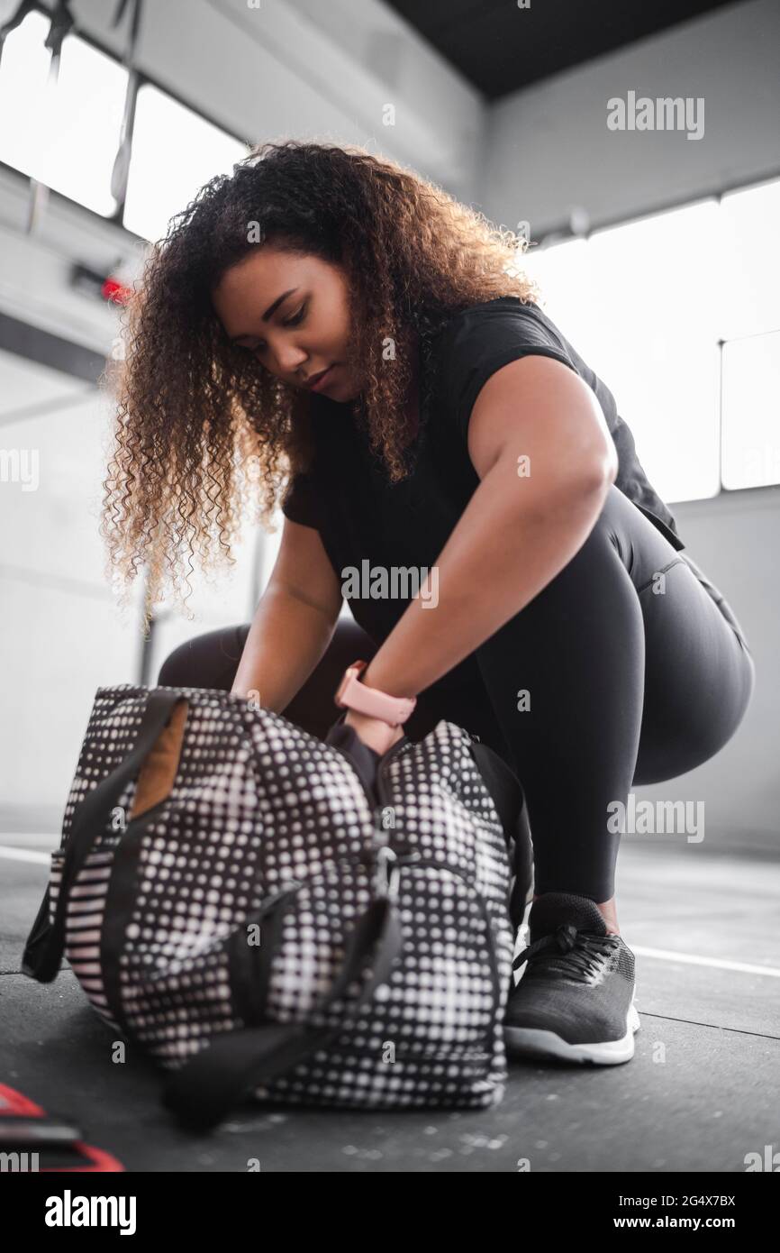 Curly haired female athlete with bag in gym Stock Photo - Alamy