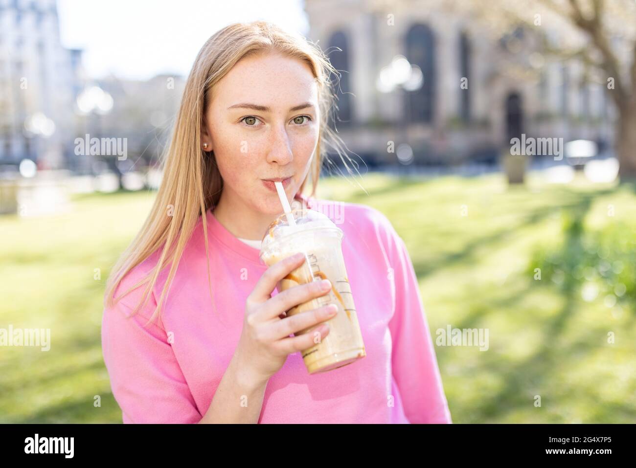 Beautiful woman drinking milkshake at public park Stock Photo - Alamy