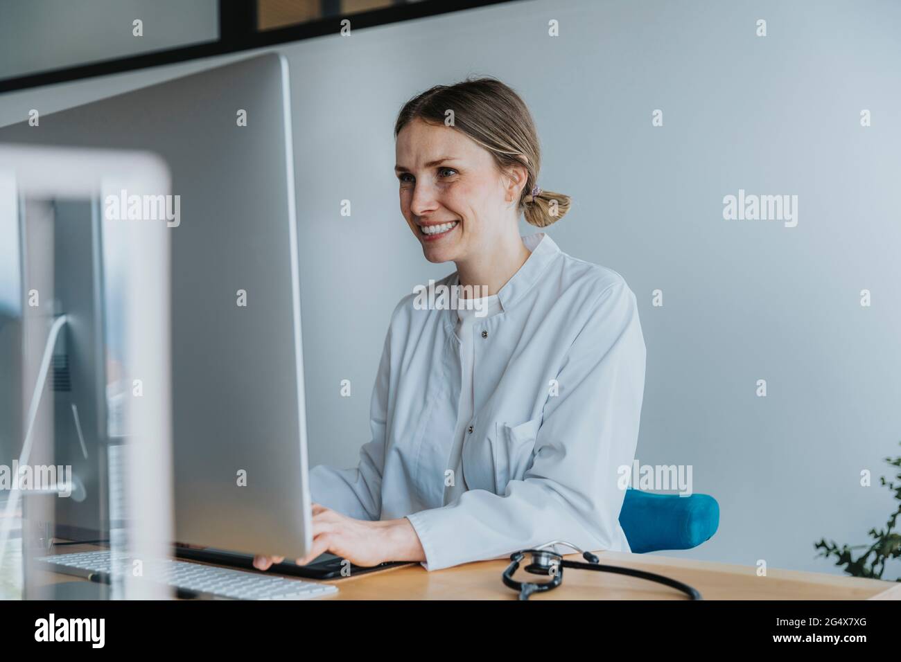 Female healthcare worker using computer at desk Stock Photo - Alamy