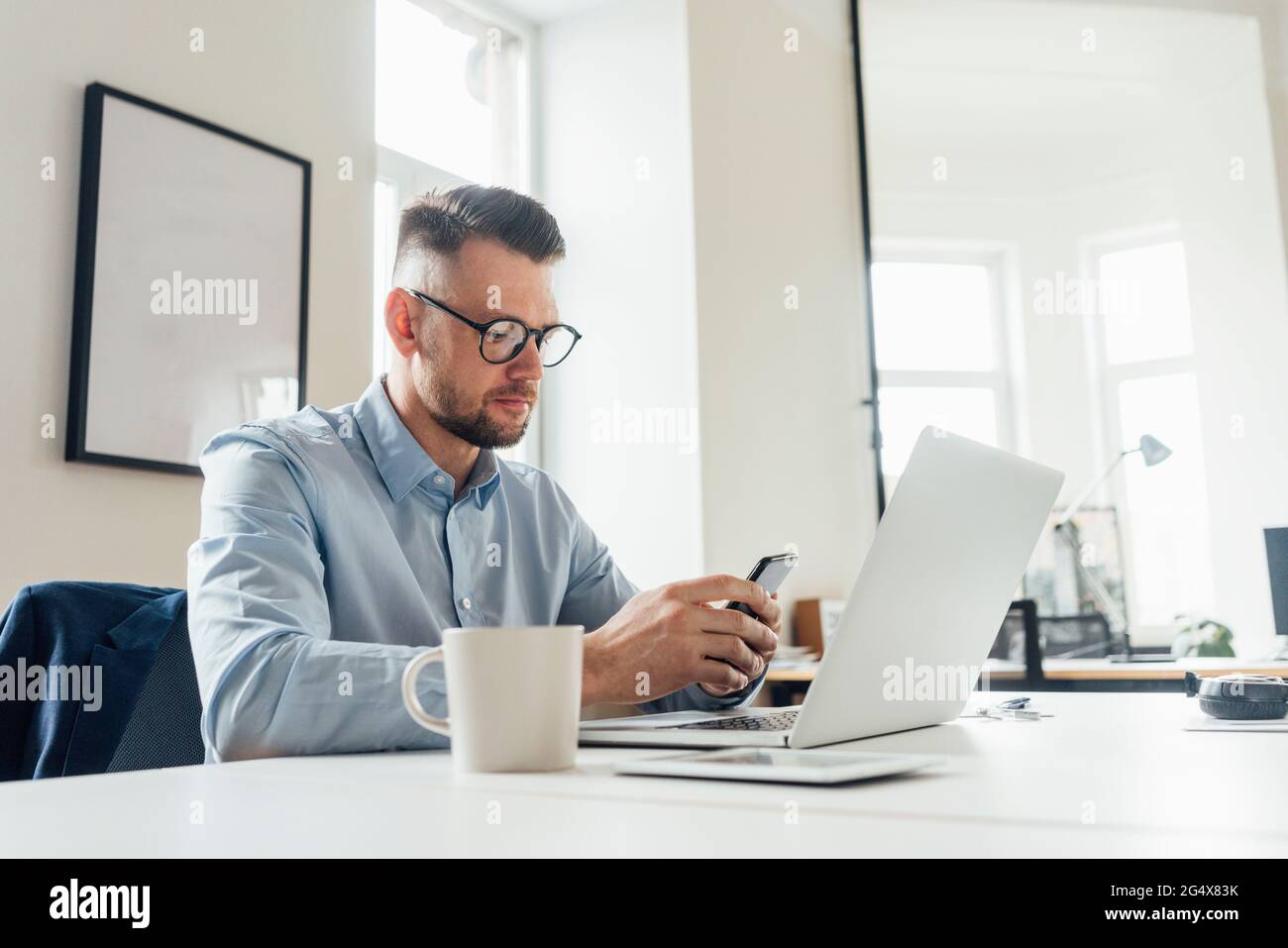 Businessman using mobile phone at place of work Stock Photo - Alamy