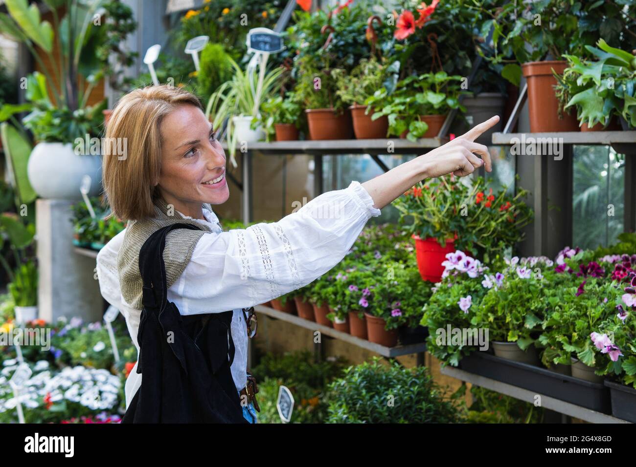 Woman pointing at potted plant in flower market Stock Photo - Alamy