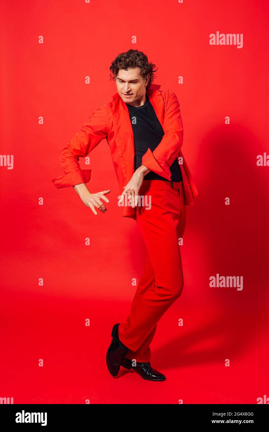 Portrait of a tall handsome man dressed in red shirt posing on the red ...
