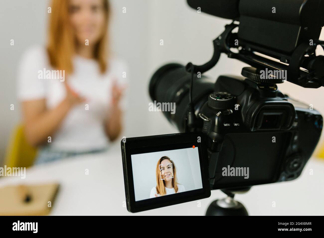 Smiling female influencer filming through camera at home Stock Photo ...