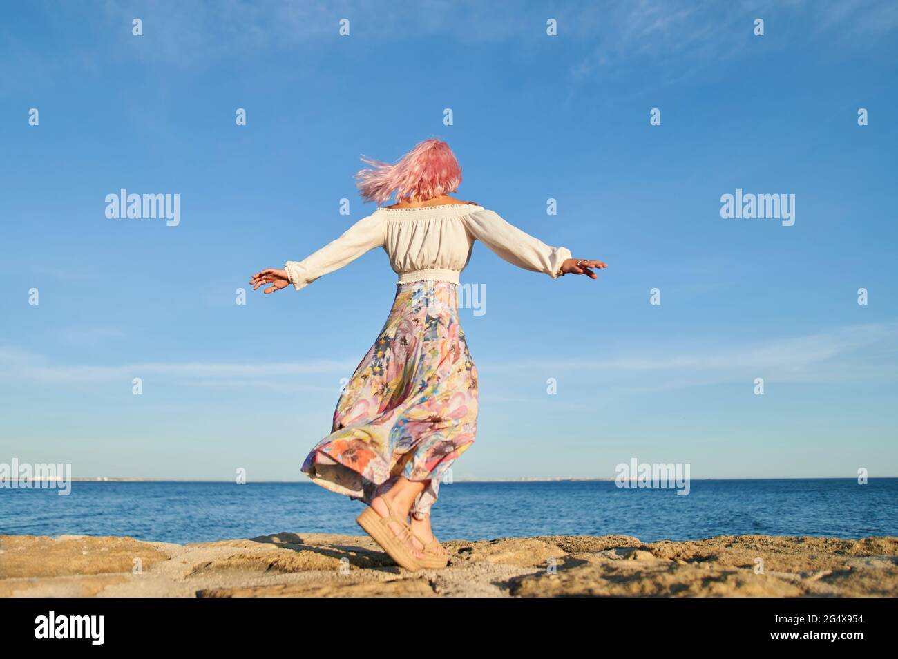 Young woman with arms outstretched spinning at beach Stock Photo - Alamy
