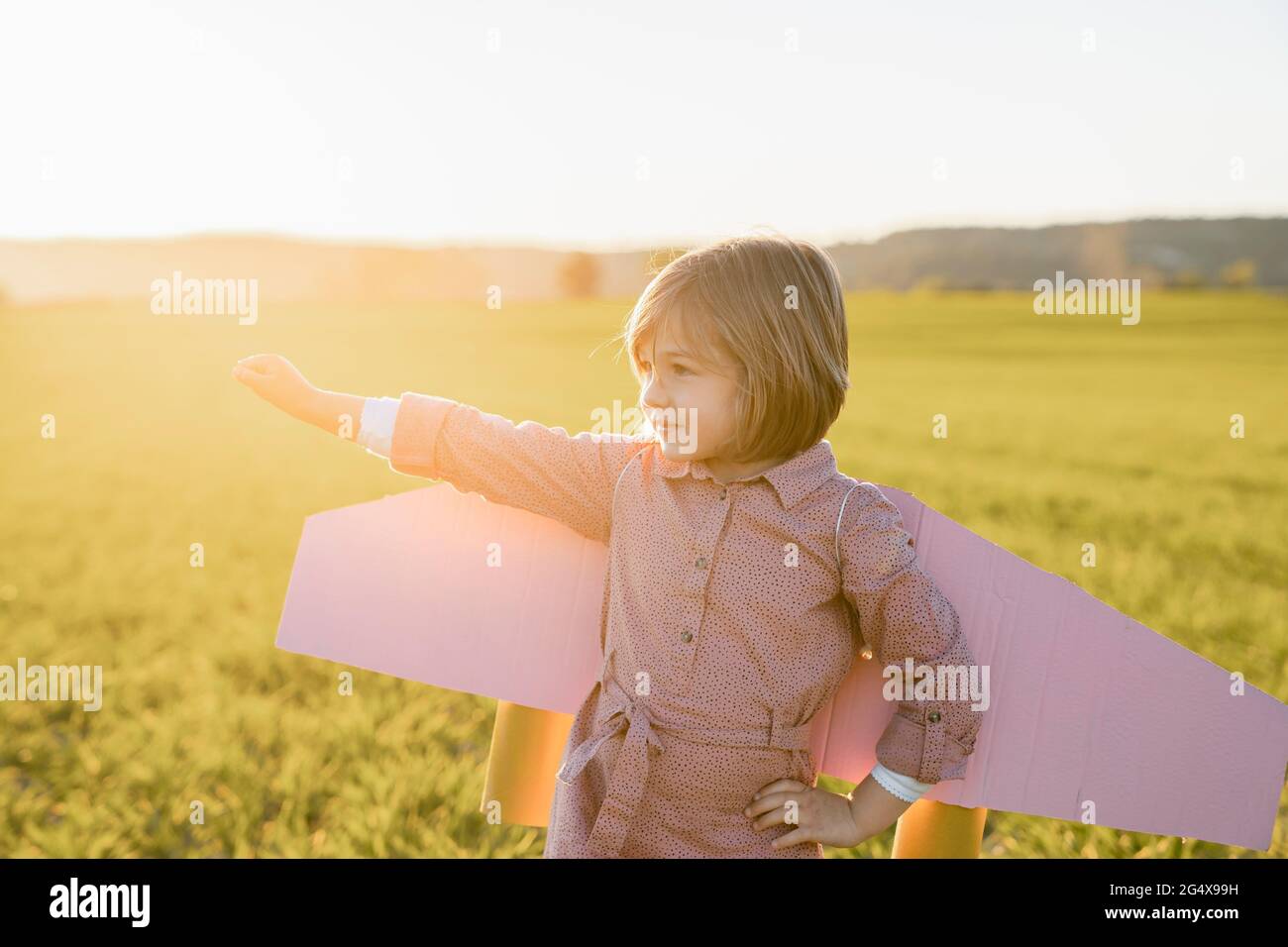 Little girl wearing rocket wings standing with hand on hip looking away ...