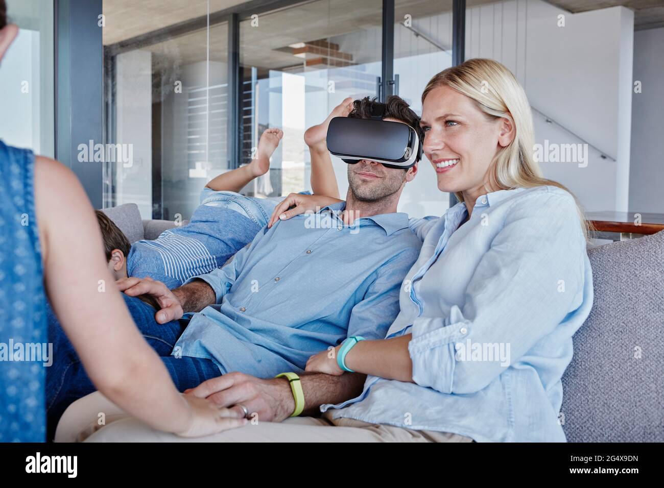 Man wearing virtual reality simulator sitting by woman while children ...