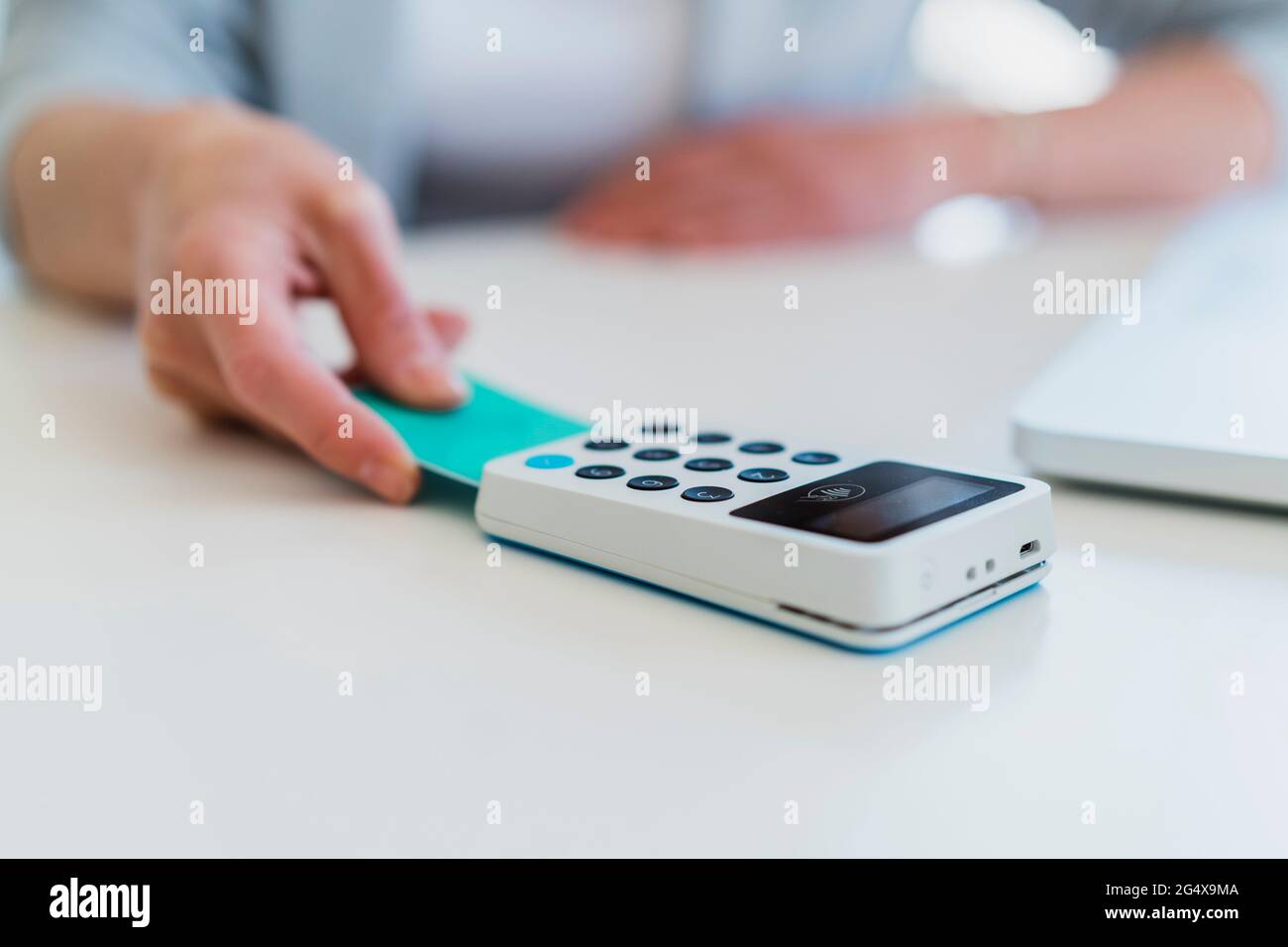 Businesswoman scanning credit card through terminal at desk Stock Photo ...