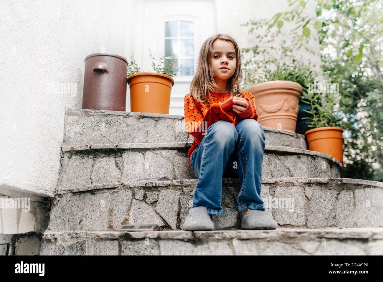 Girl sitting on steps at entrance of house Stock Photo - Alamy